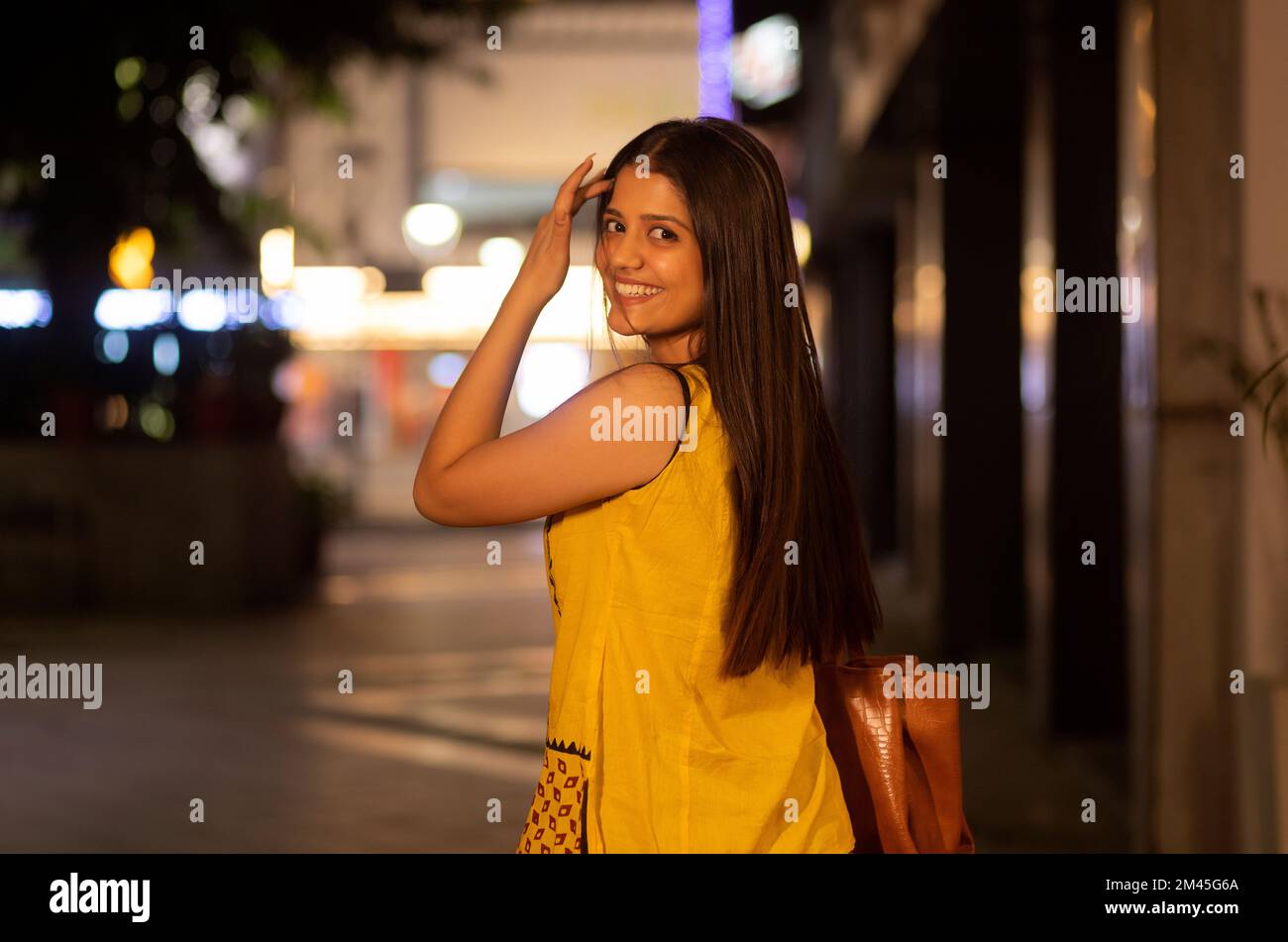 Woman looking back at camera with smile while walking on street Stock ...