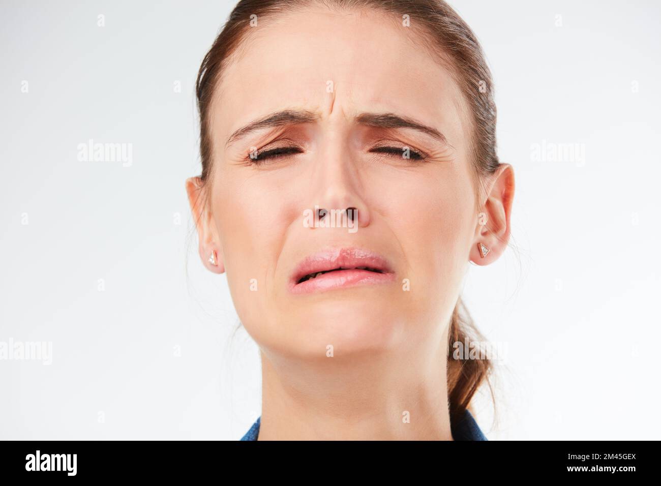 Why me. Studio shot of a young woman crying against a grey background ...
