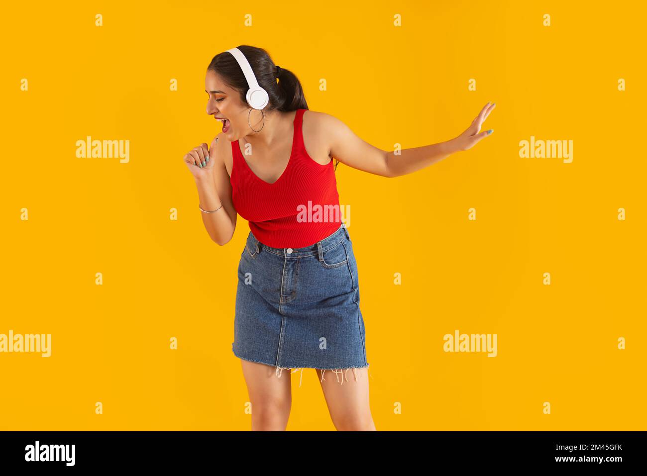 Teenage girl singing while listening music over headphones Stock Photo ...