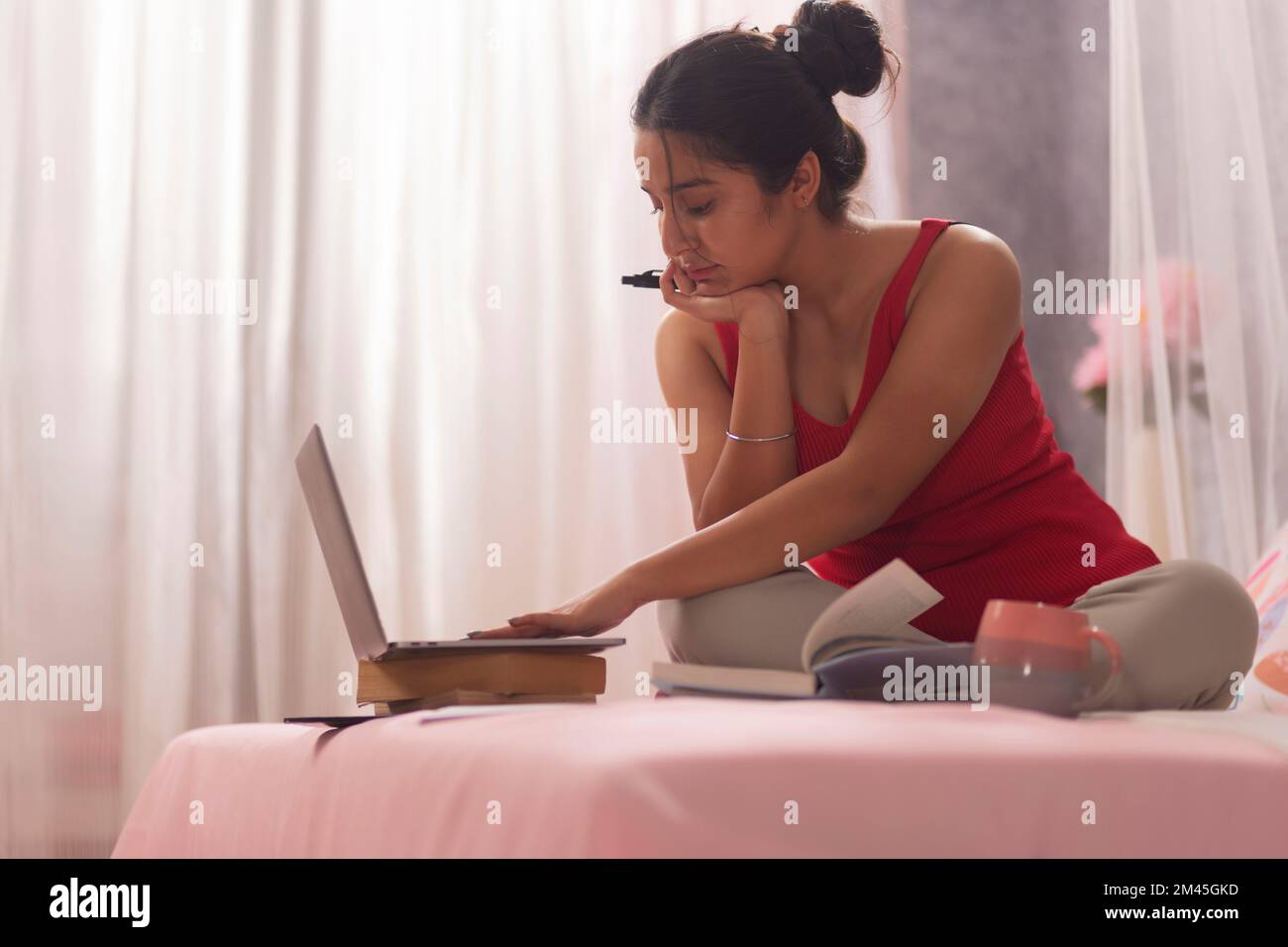 Portrait of teenage girl studying with laptop in bedroom Stock Photo ...
