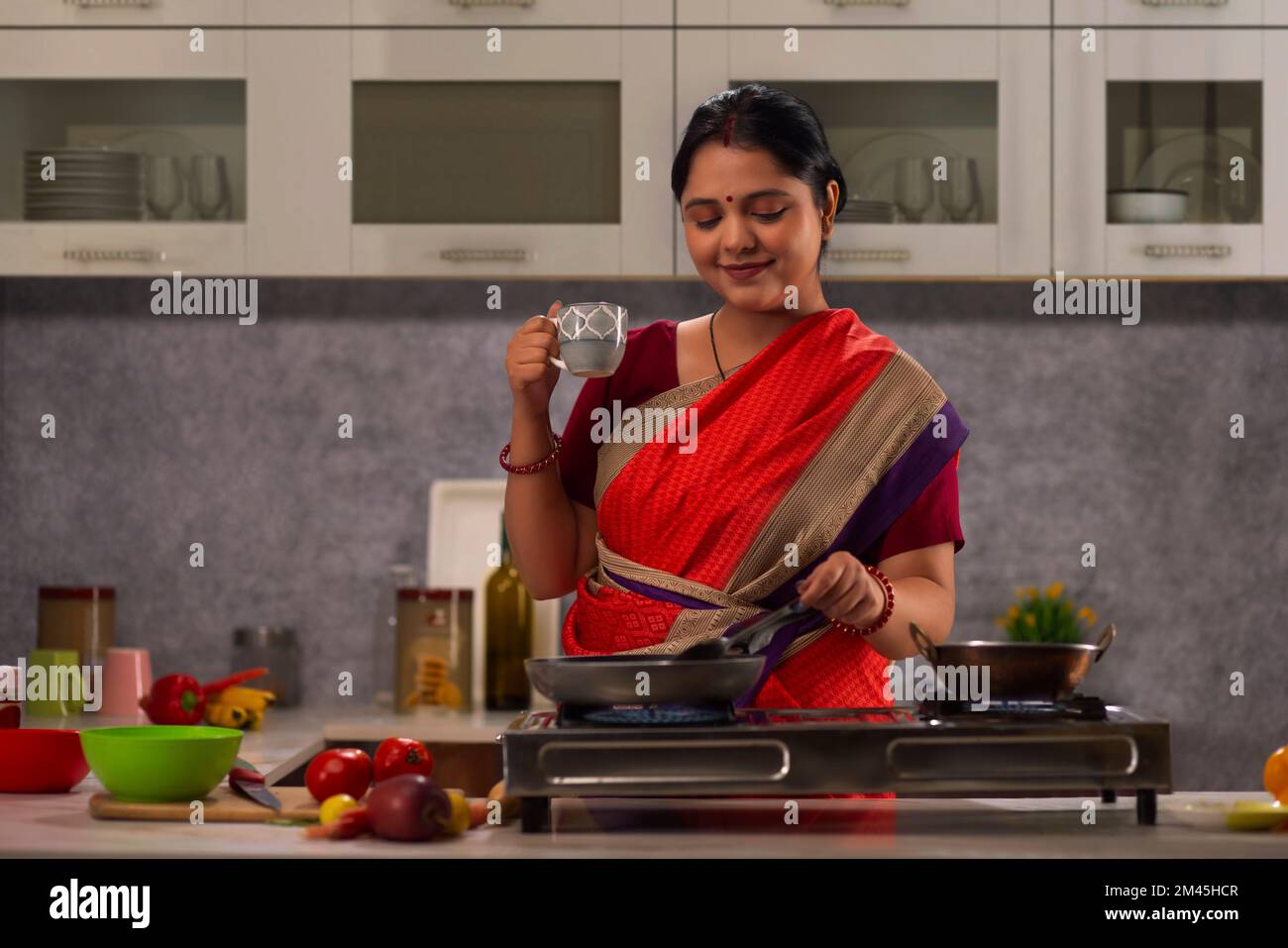 Woman drinking tea while cooking in the kitchen Stock Photo - Alamy