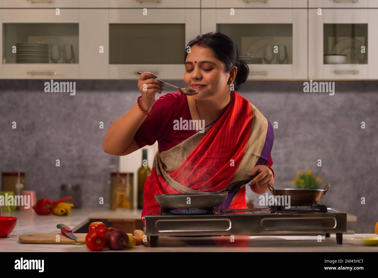 Young woman smelling food while cooking in the kitchen Stock Photo - Alamy