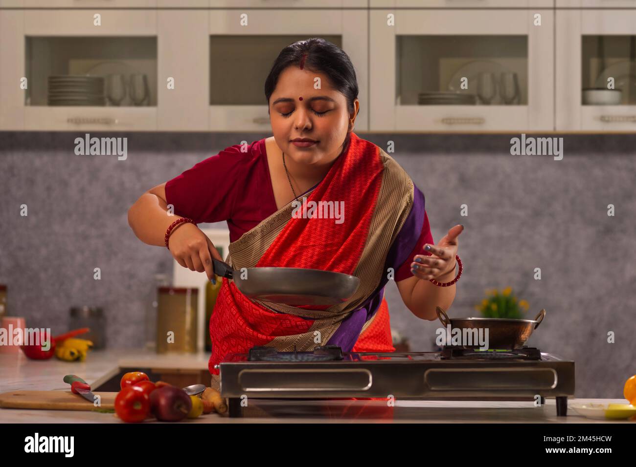 Young woman smelling food while cooking in the kitchen Stock Photo - Alamy