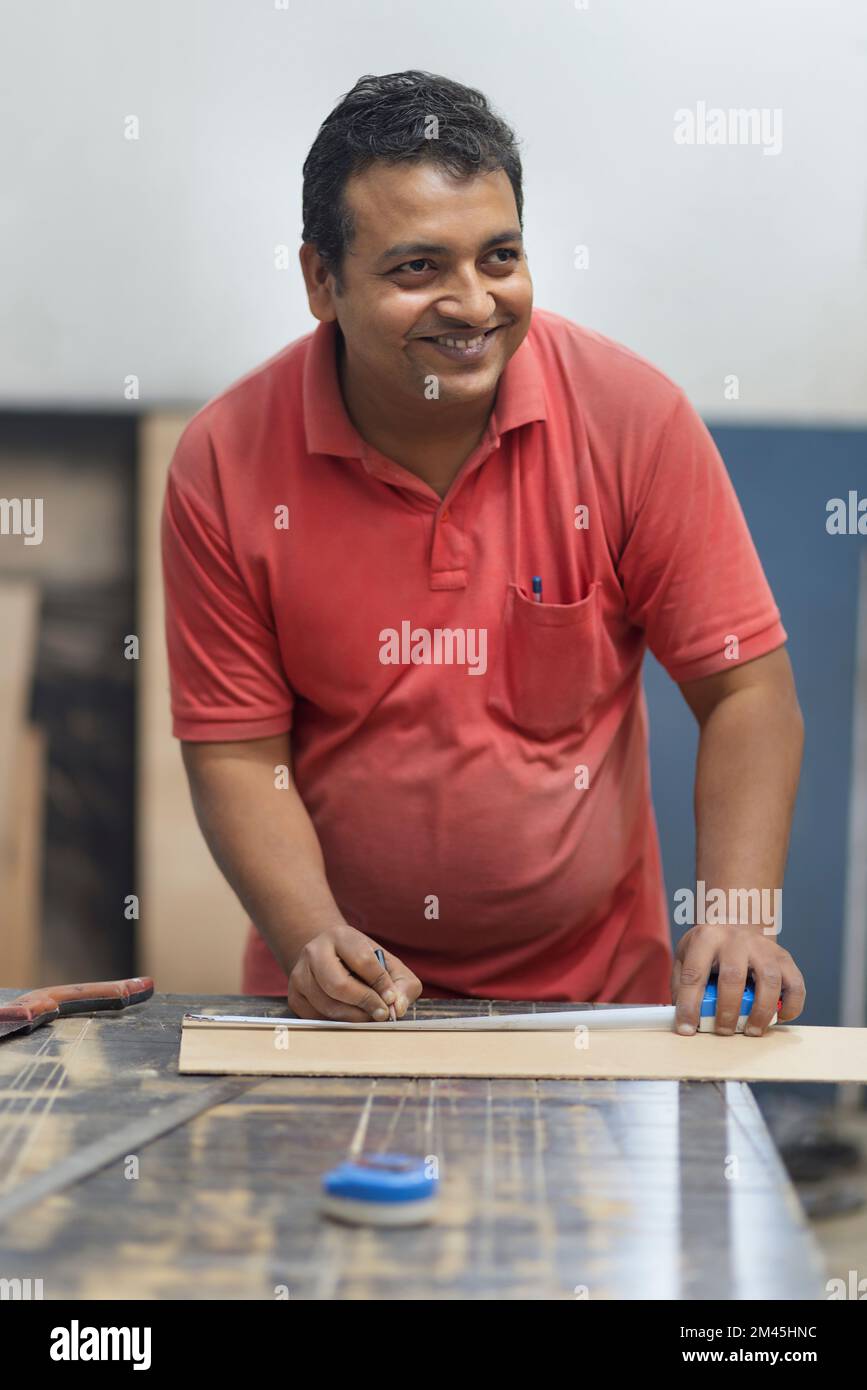 Male carpenter measuring the board Stock Photo - Alamy
