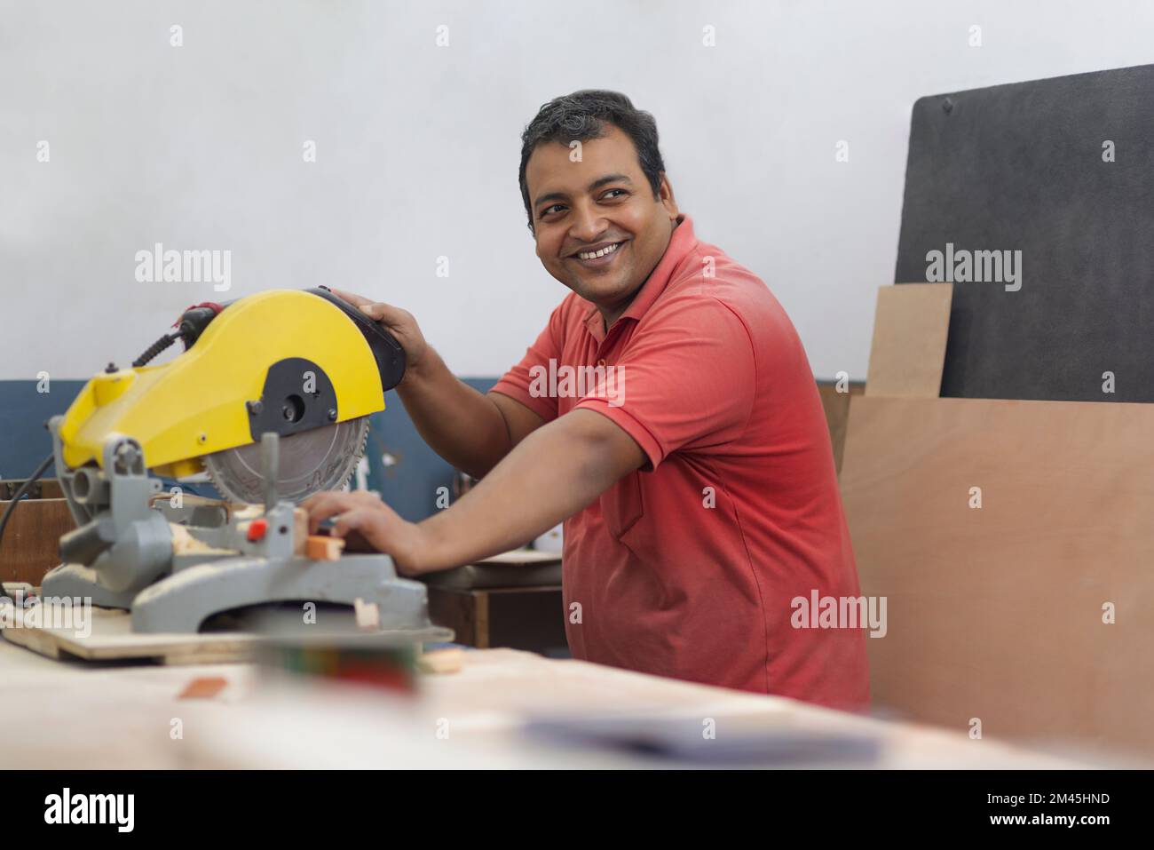 Young carpenter cutting a piece of wood with a hand circular saw Stock ...