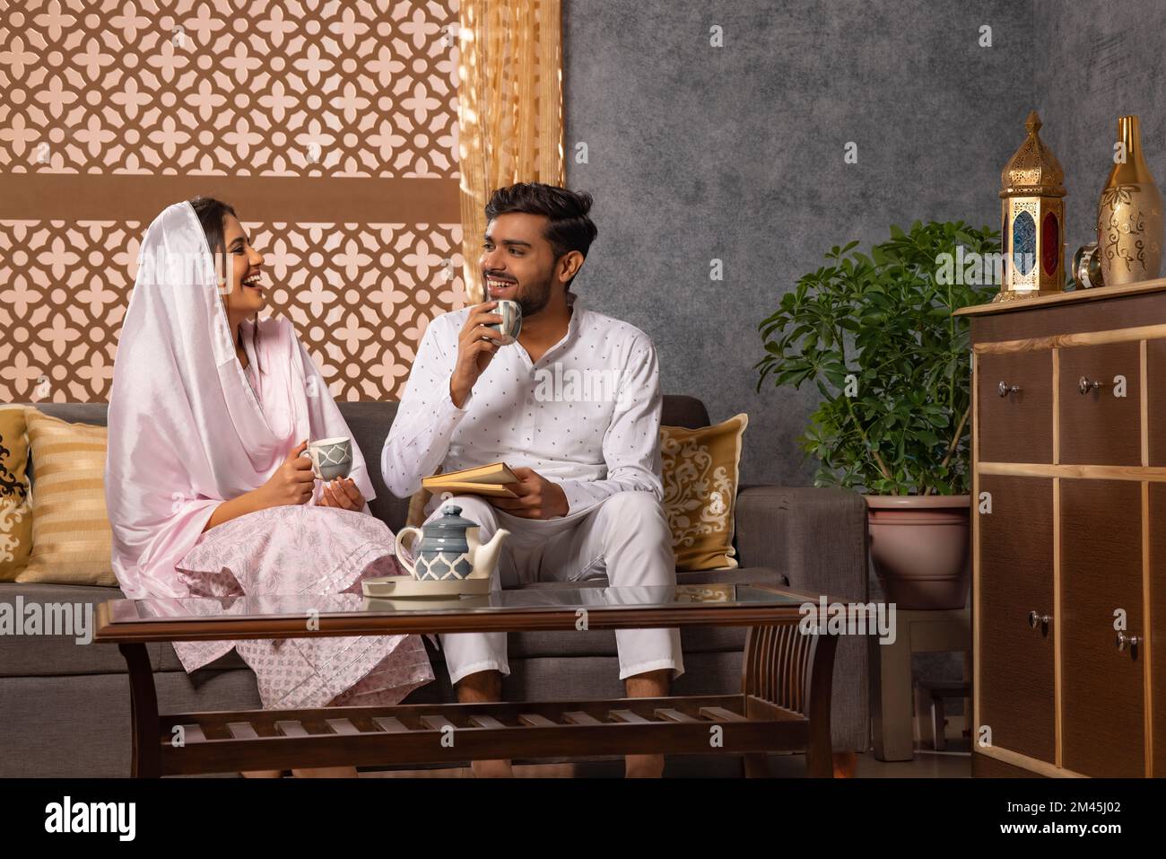 Happy Muslim couple drinking tea together in living room Stock Photo ...