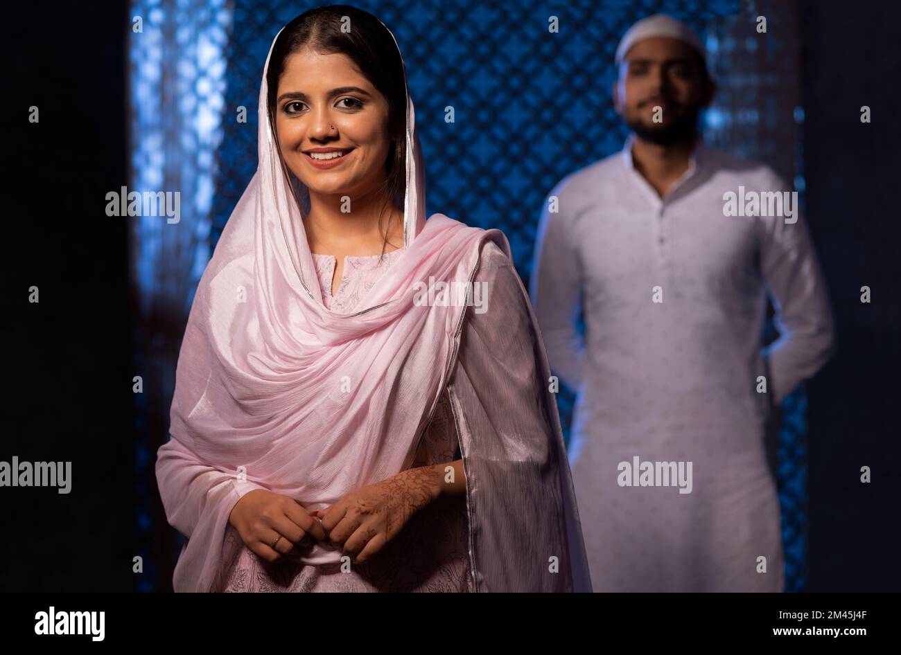Muslim woman looking at camera with smile while her husband standing ...