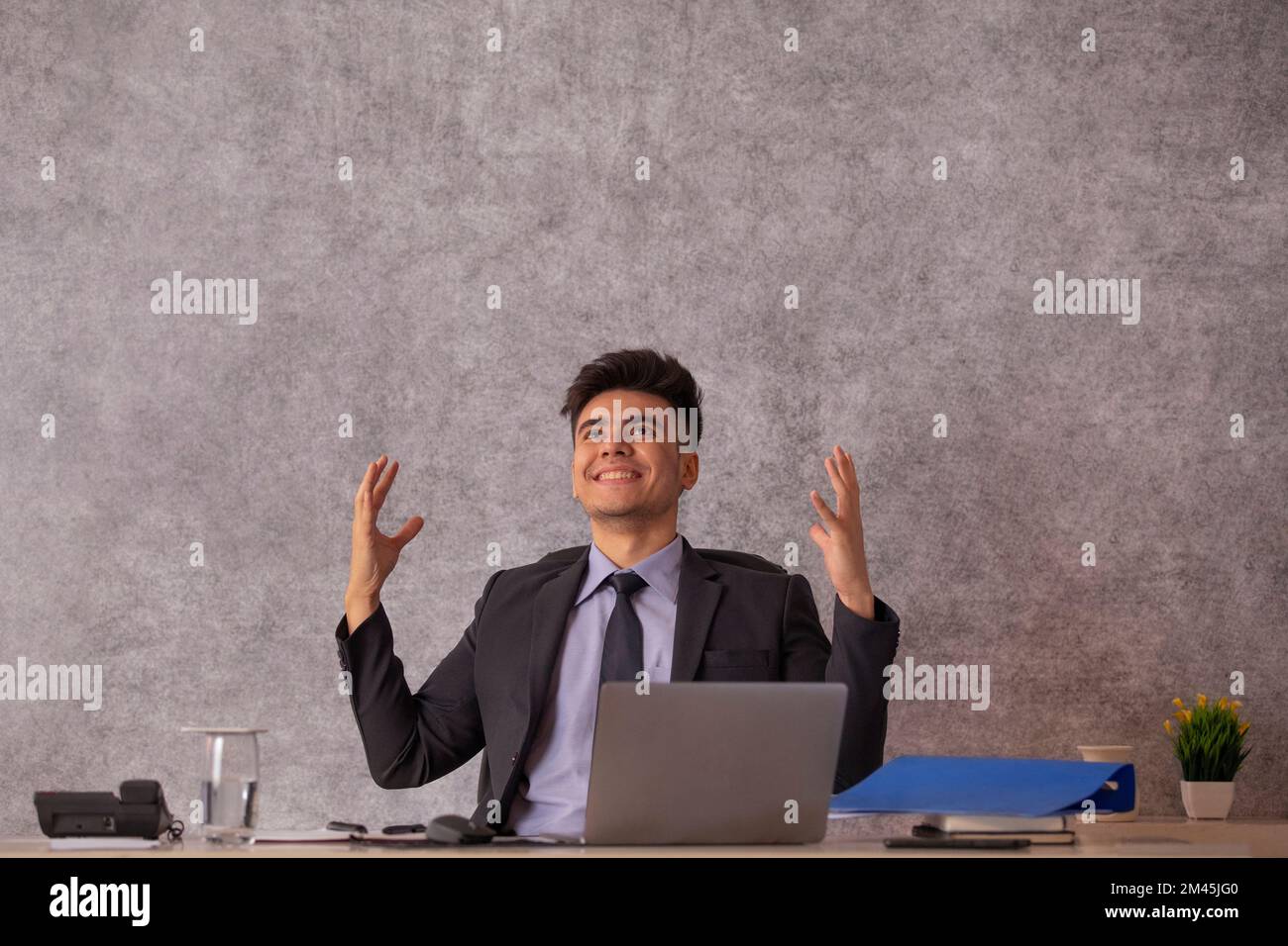 Young businessman raising arms up and celebrating finished work project ...