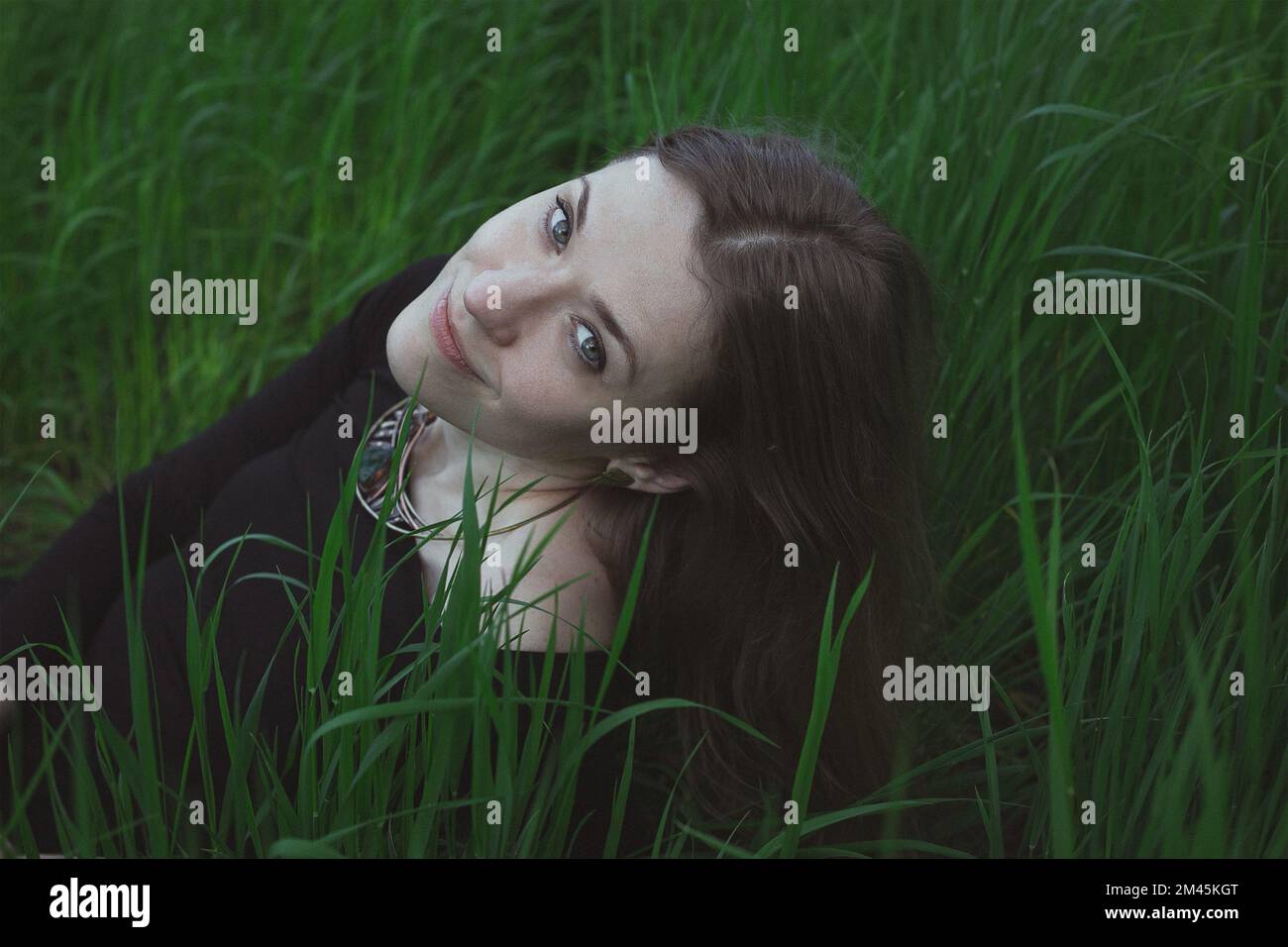 Close up smirking woman in tall grass staring directly into camera ...