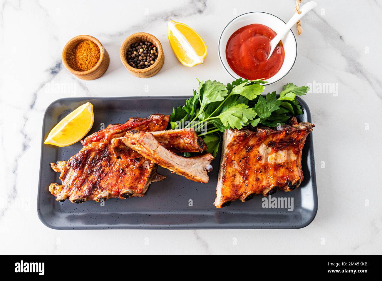 grilled pork ribs on a ceramic rectangular plate with fresh tomato ...
