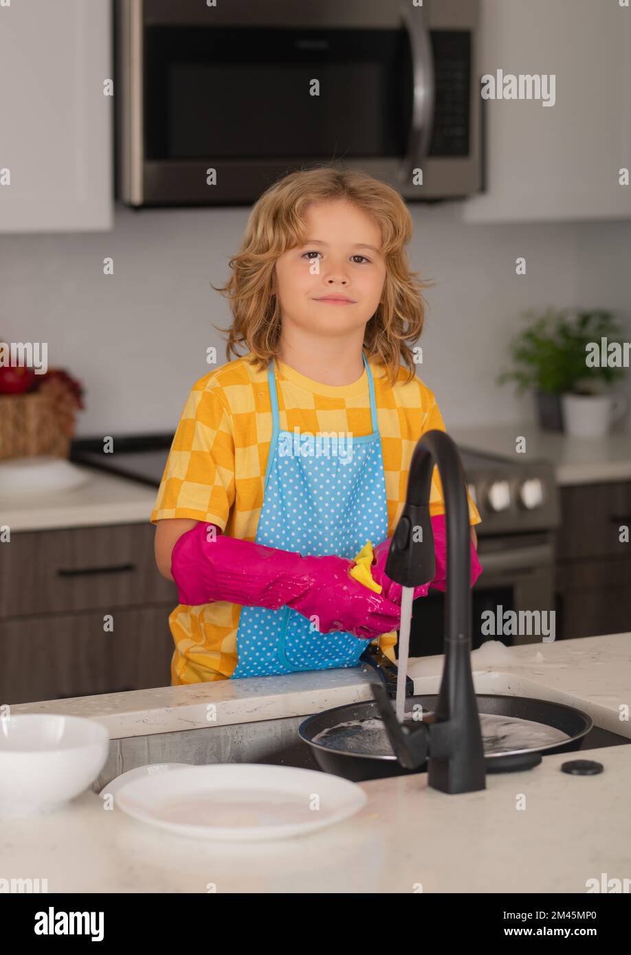 Child help in washing dishes at kitchen. Kid cleaning of kithen, help ...
