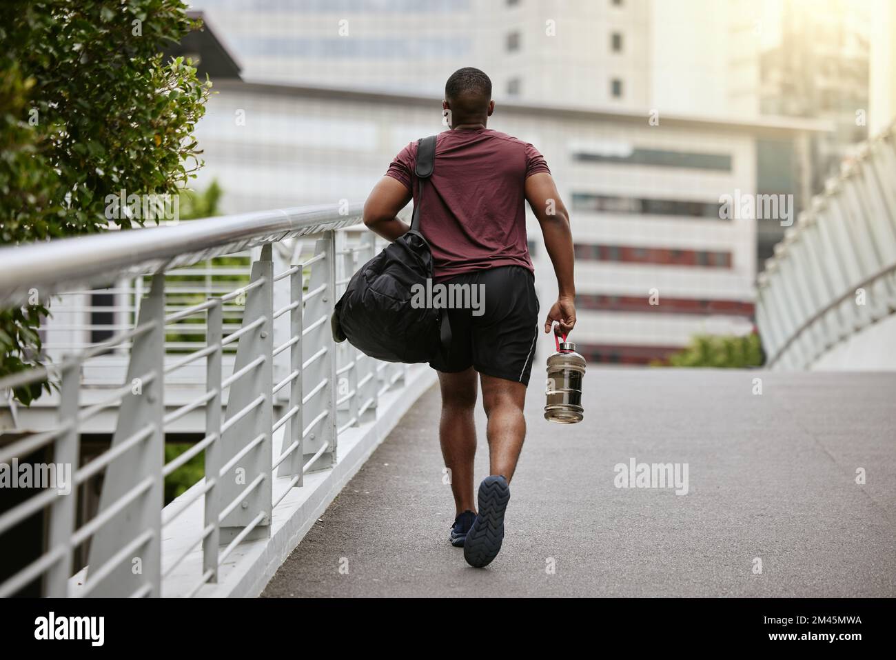 Fitness, city or black man walking to gym on a bridge with a sports bag ...