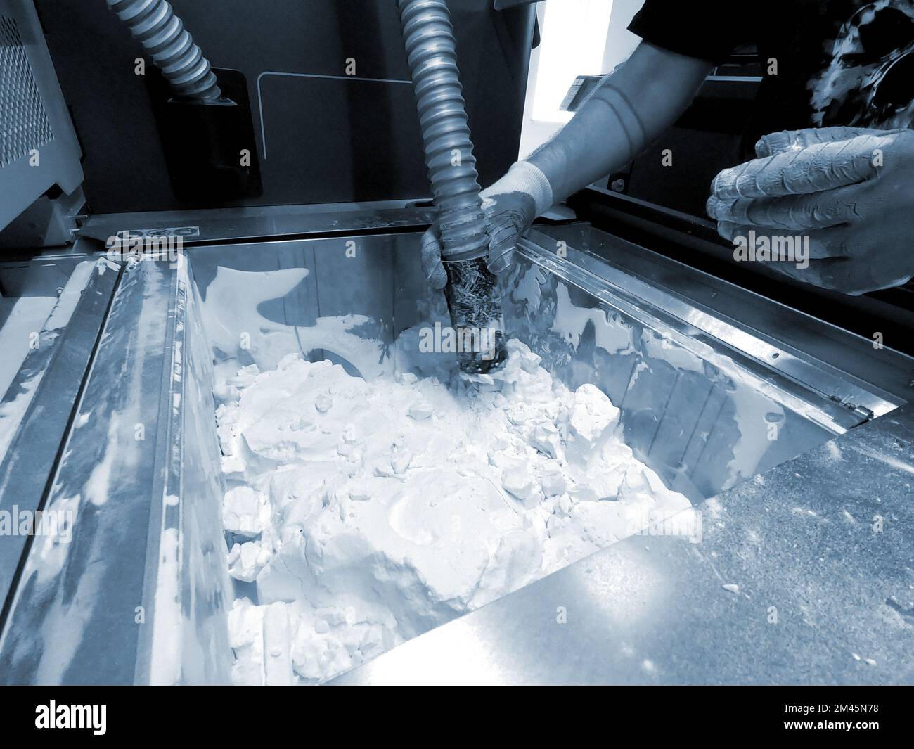 Mane taking out models from white polyamide powder in working chamber ...