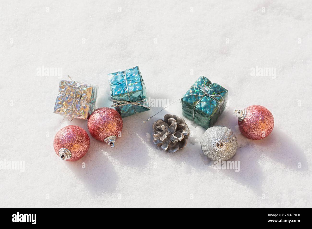 Snow Christmas decorations. Silver blue pink shiny balls gifts lie on ...