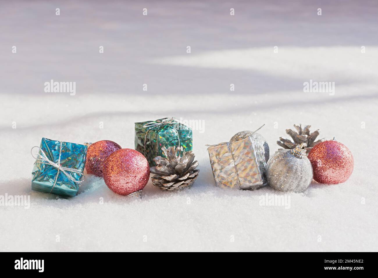 Snow Christmas decorations. Silver blue pink shiny balls gifts lie on ...