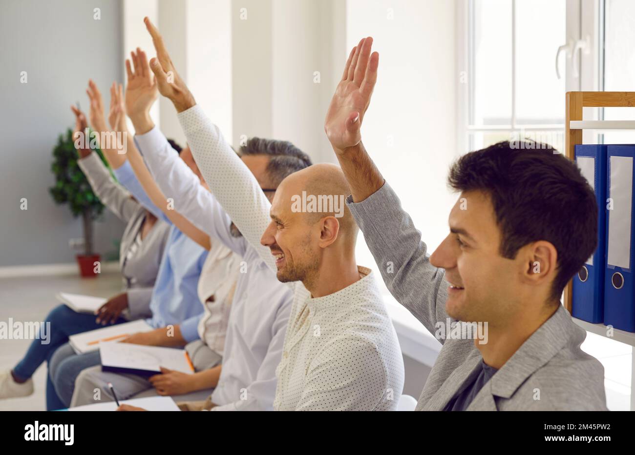 Group of satisfied business people raise their hands to ask questions ...