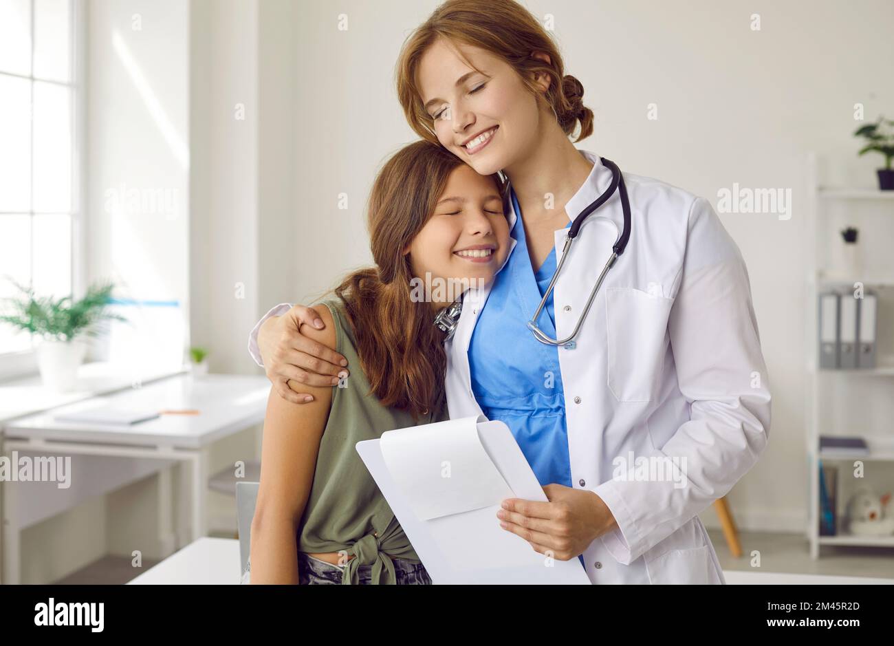 Happy pediatrician standing in medical office, hugging child patient ...