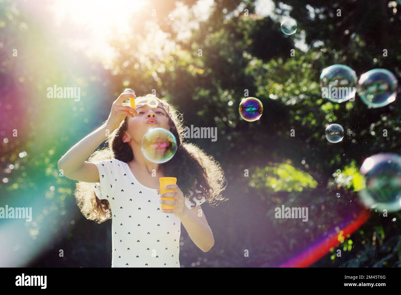Bubbles all around. a cheerful little girl blowing bubbles in the ...
