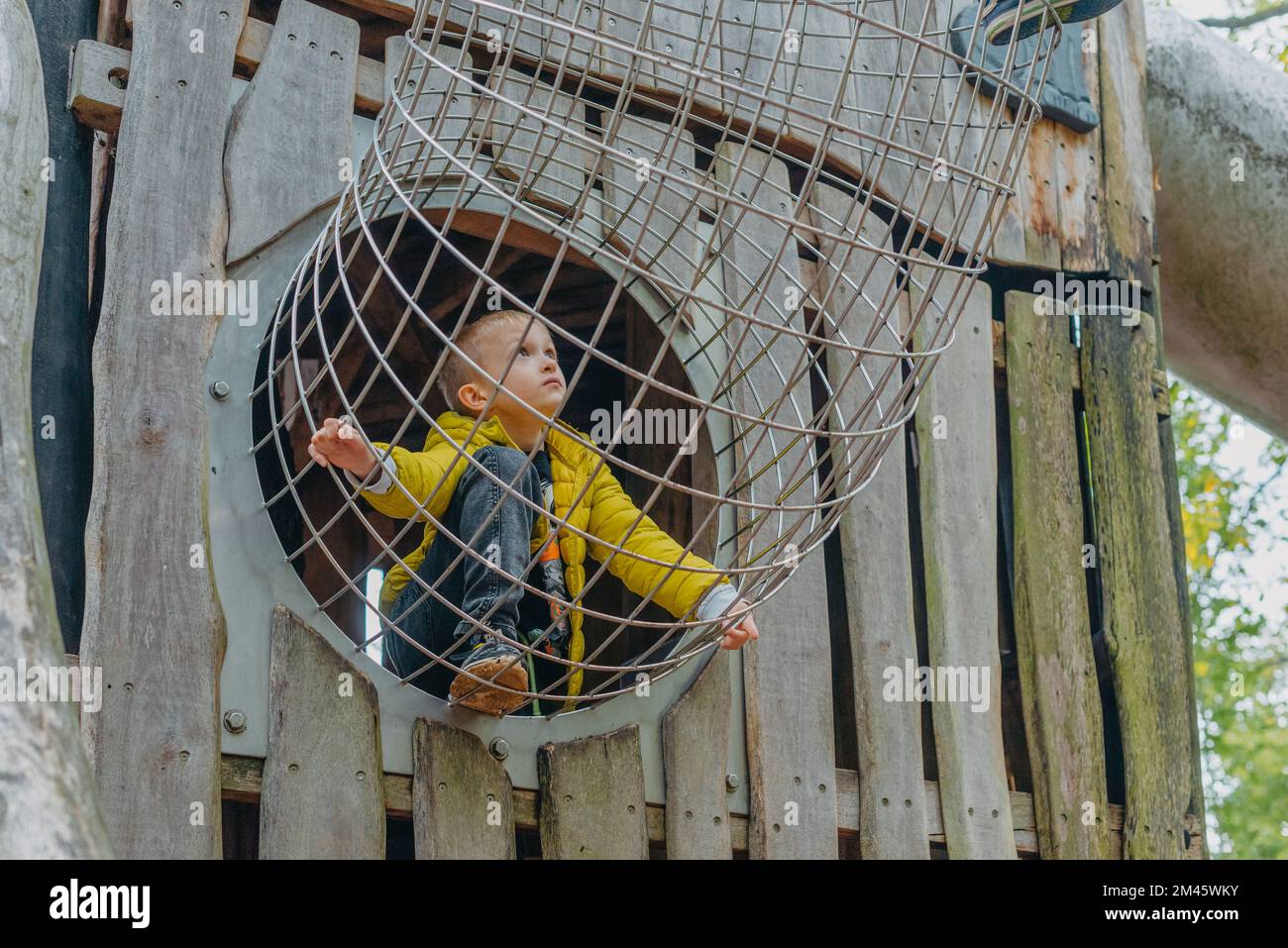 A child climbs up an alpine grid in a park on a playground on a hot ...