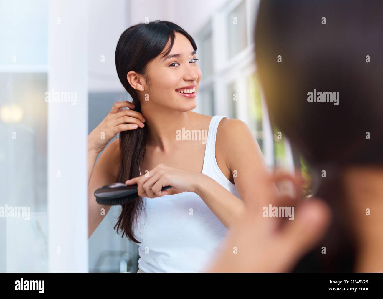My hair is flawless. a cheerful attractive young woman brushing her ...