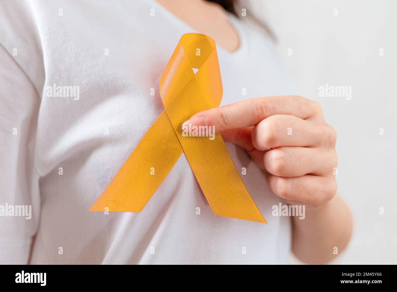 A woman's hand attaches a gold ribbon - a symbol of childhood cancer-to ...