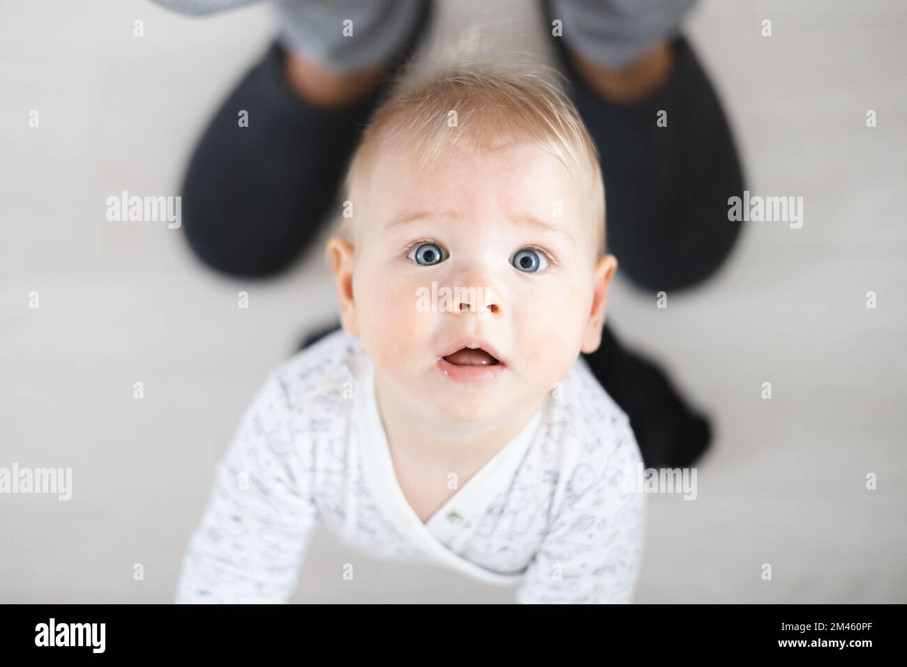 Top down view of cheerful baby boy infant taking first steps holding to ...