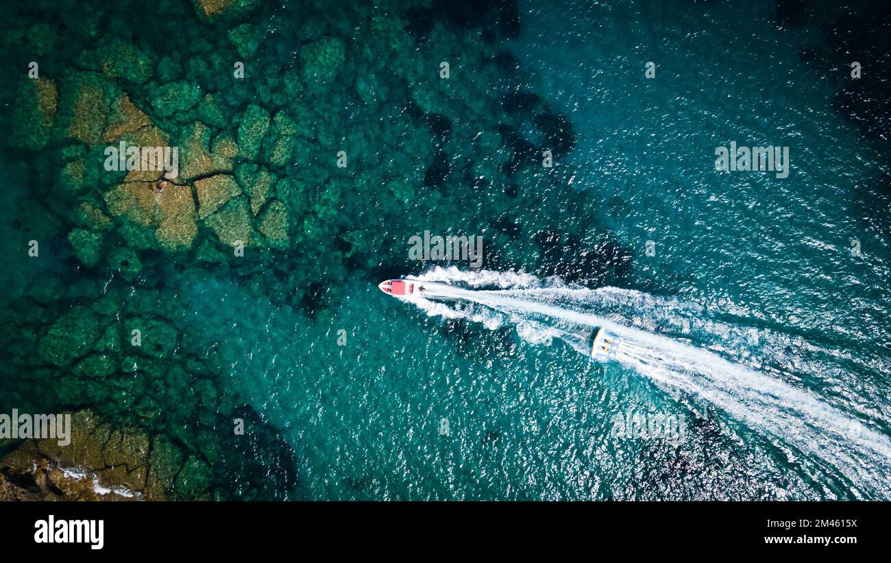 An aerial top view of a motor boat leaving water trails on a beautiful ...