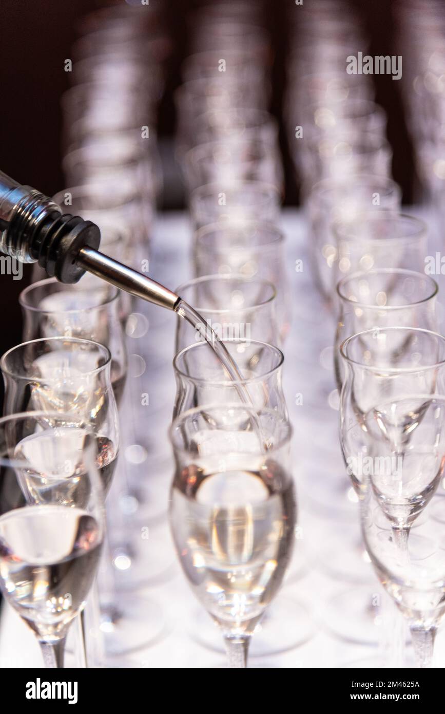 A vertical shot of a person pouring alcoholic drink from a bottle into ...