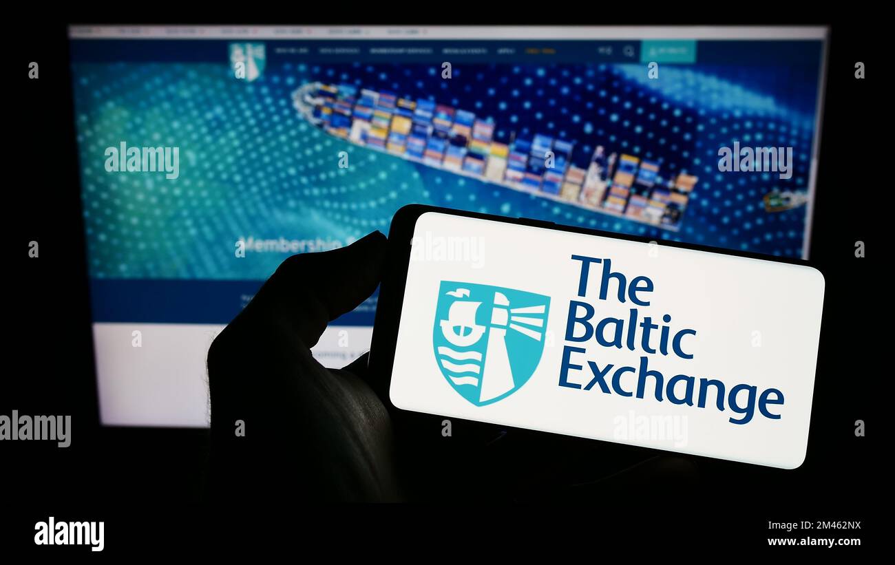 Person holding mobile phone with logo of British company The Baltic Exchange Limited on screen ...