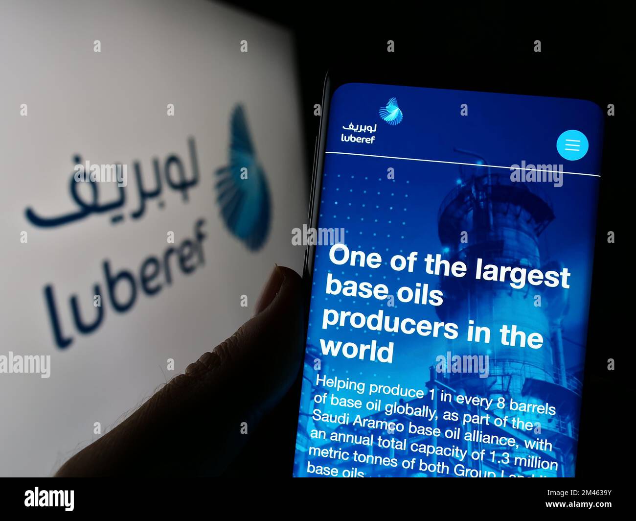 Person holding cellphone with webpage of Saudi Arabian base oil company ...