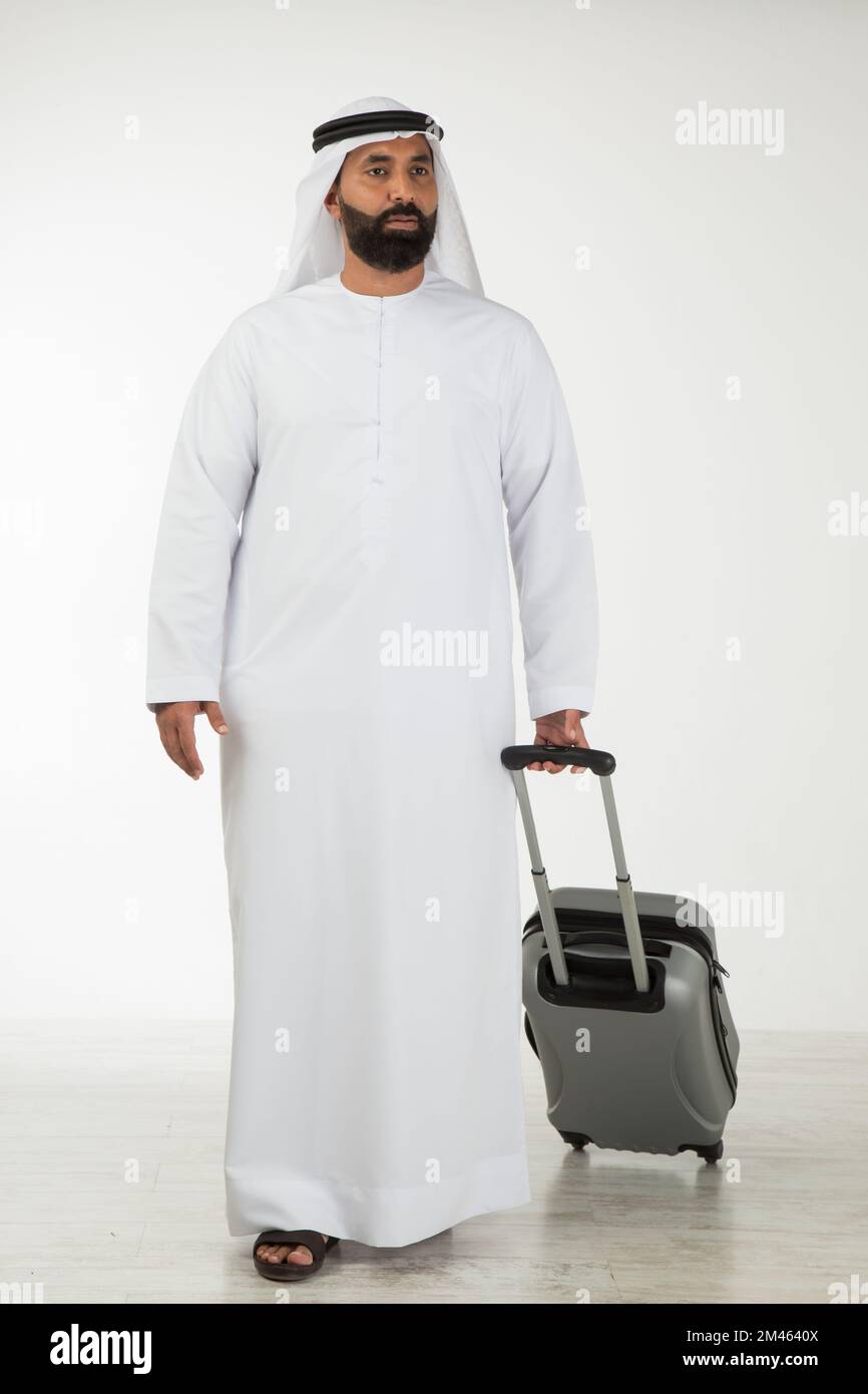 Emirati man carrying a suitcase Stock Photo - Alamy