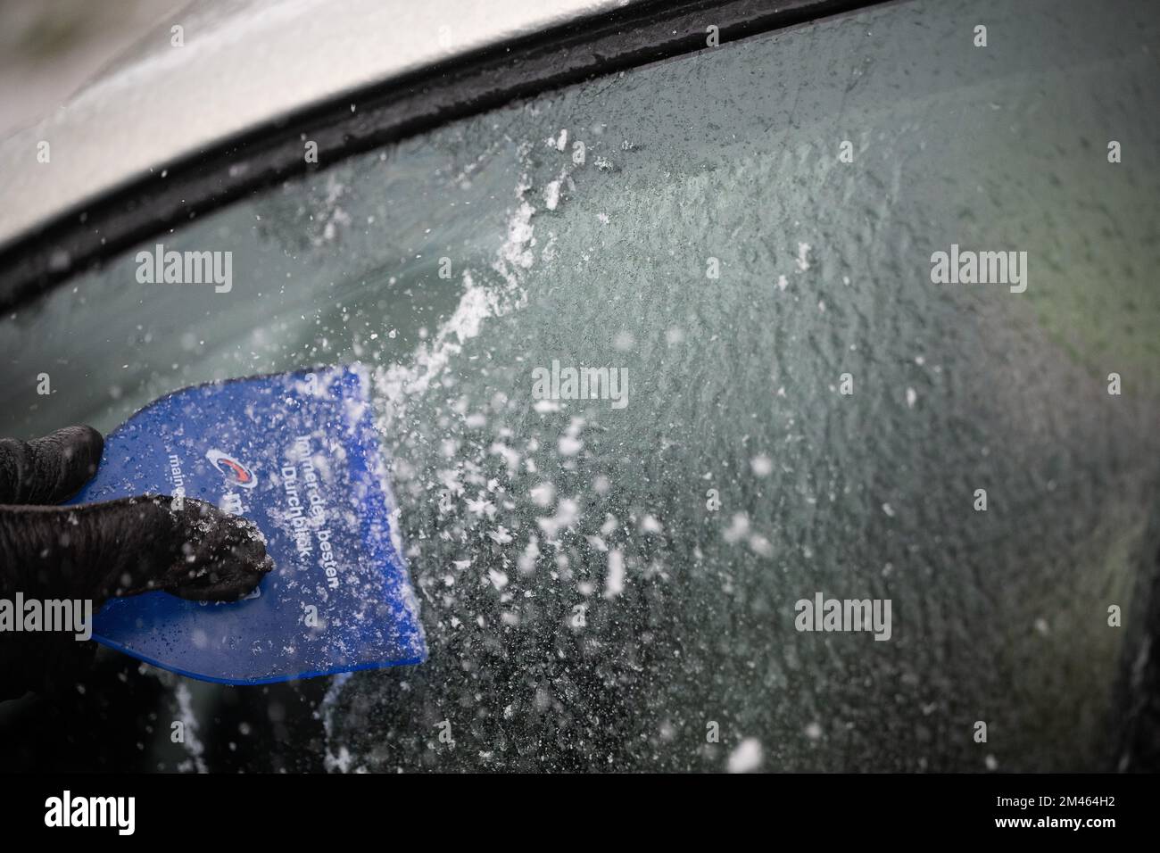 19 December 2022, Hessen, Frankfurt/Main: A man scrapes off his thickly ...