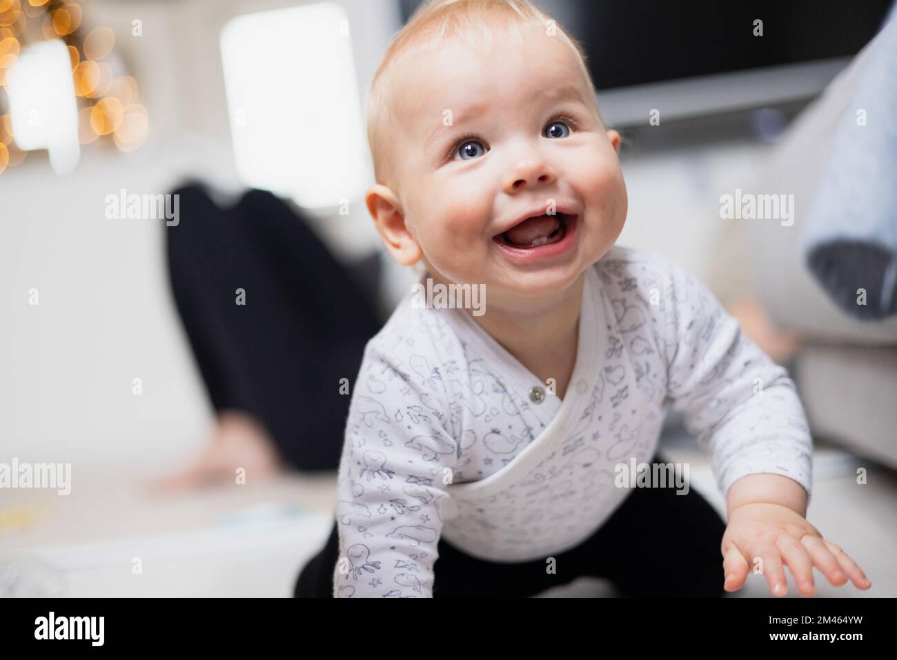 Cute infant baby boy playing, crawling and standing up by living room ...