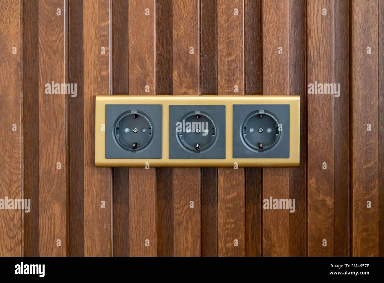 Modern triple socket mounted on wood veneer wall Stock Photo - Alamy