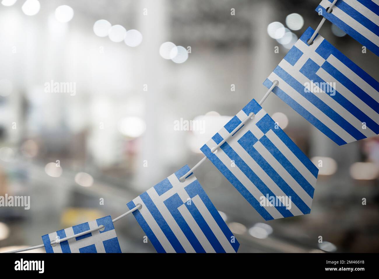 A garland of Greece national flags on an abstract blurred background ...