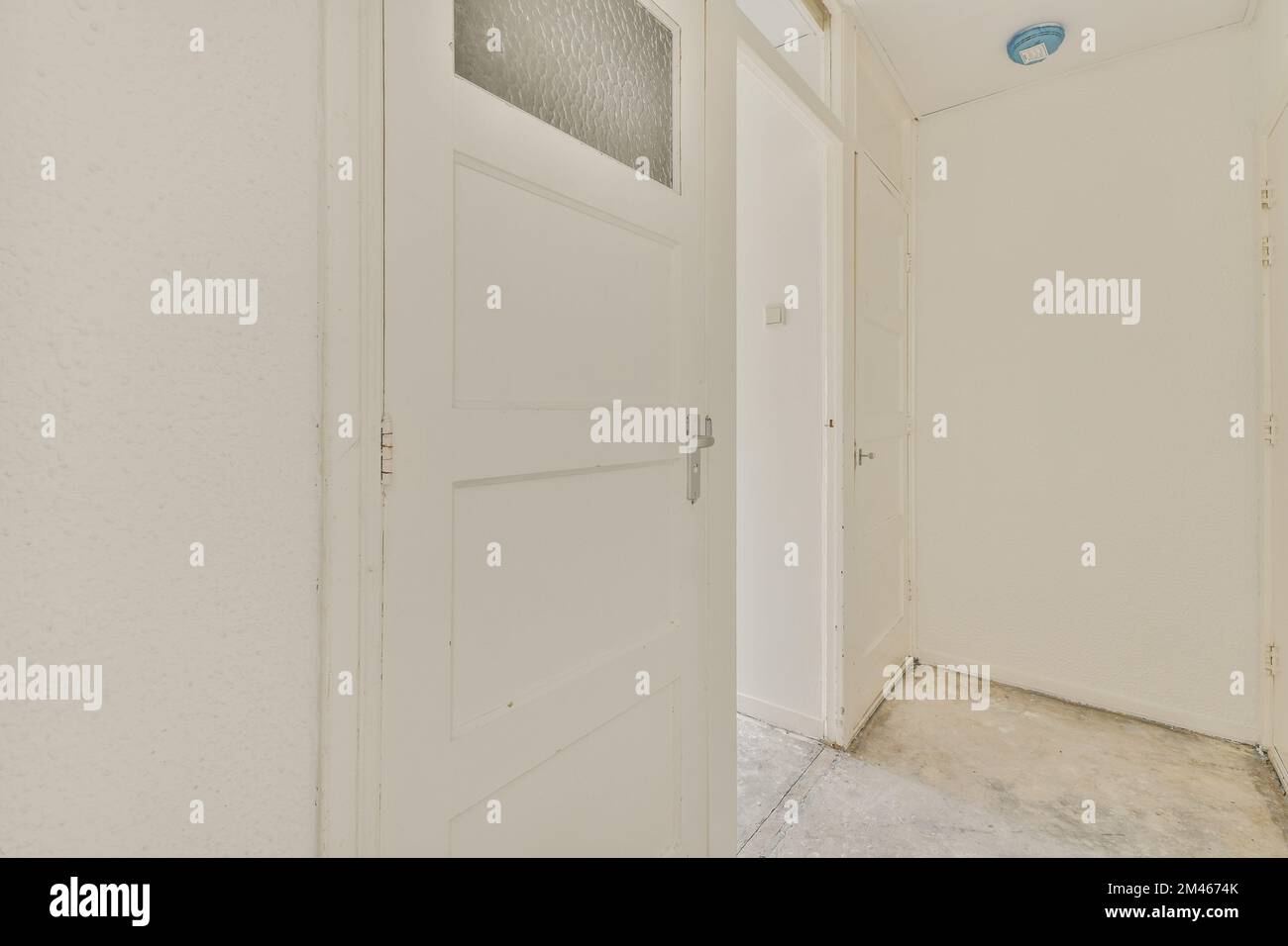 Light narrow hallway with many doors in white walls and shabby floor ...