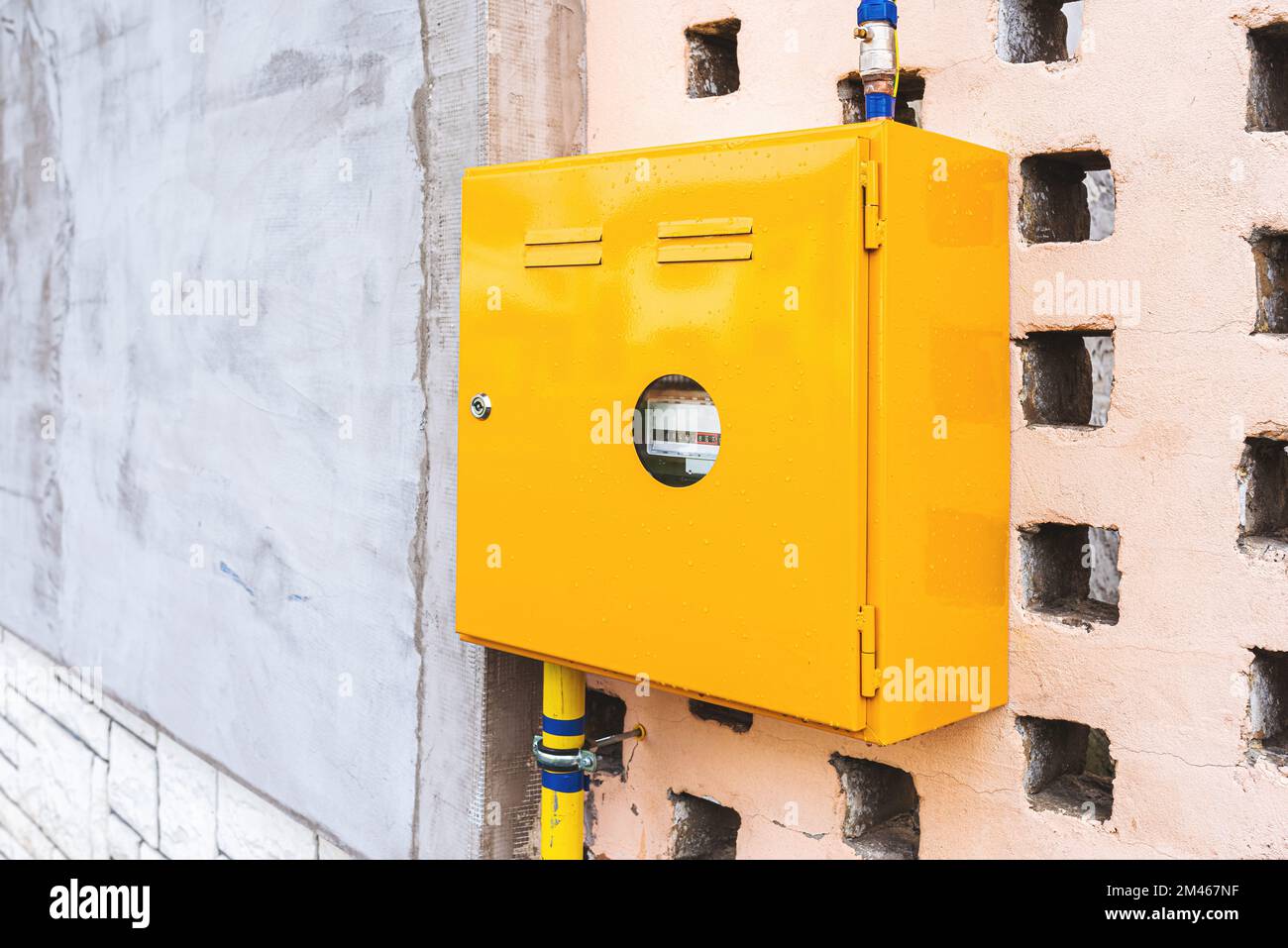 Gas meter in yellow metallic box attached to a wall of house, selective ...