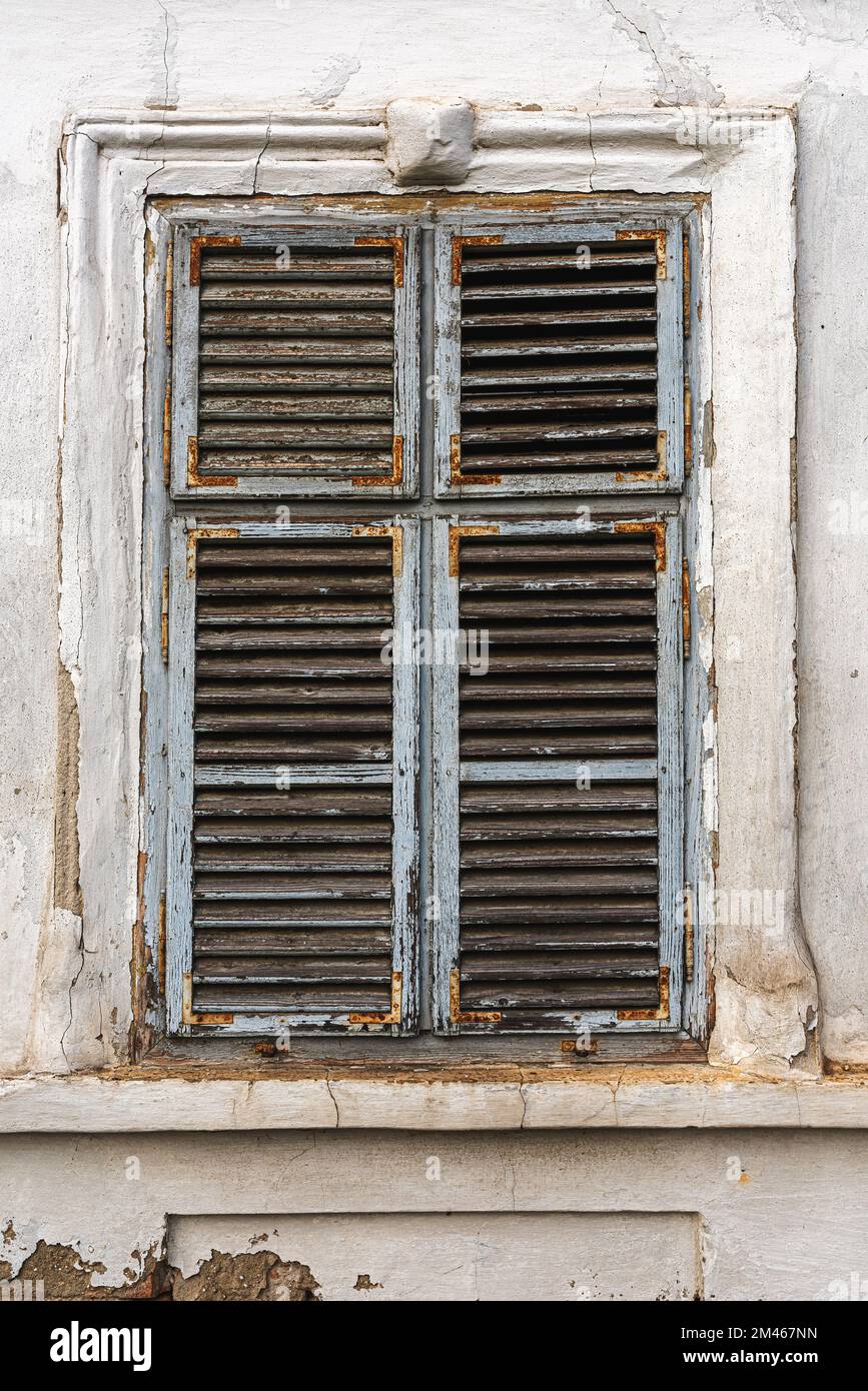 Old window with worn wooden shutters on exterior wall of an old ruined ...