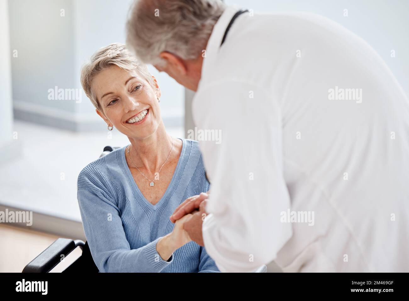 Senior woman, wheelchair and doctor holding hands in hospital support ...