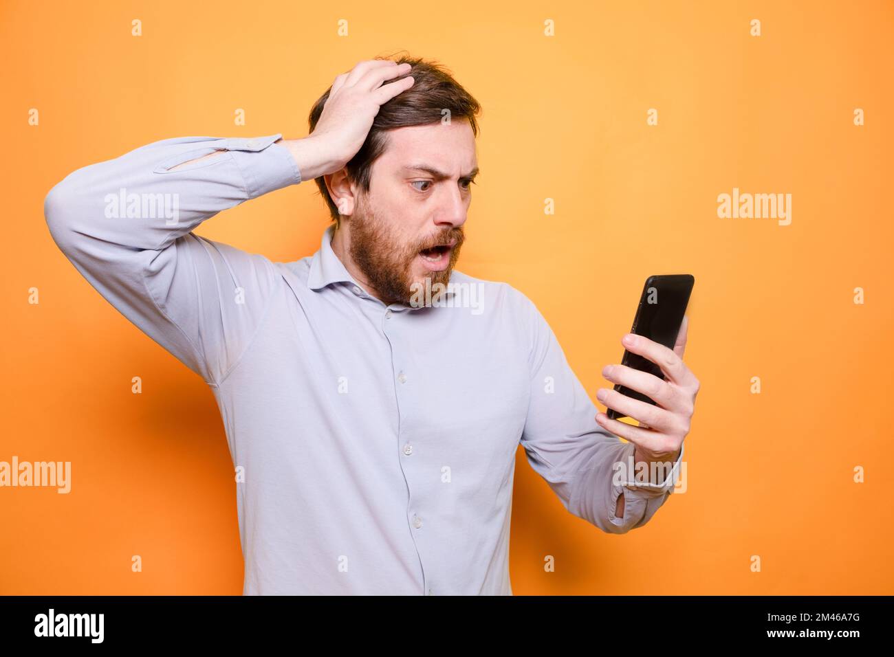 Surprised man looks shocked at the phone on a yellow background Stock ...