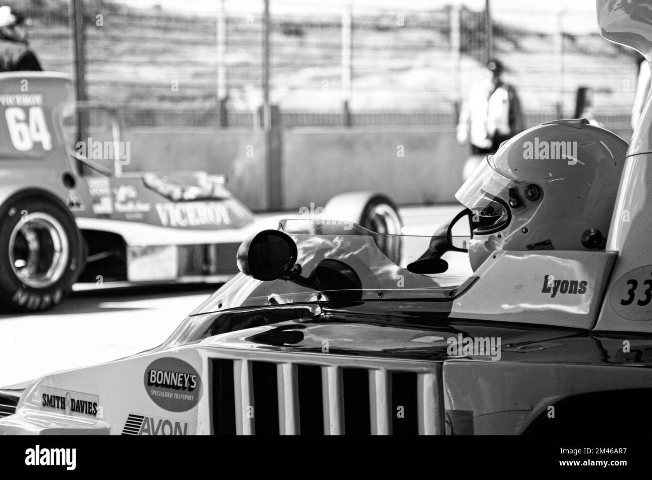 Photo of a driver wearing a safety helmet, sitting in a vintage Lola ...