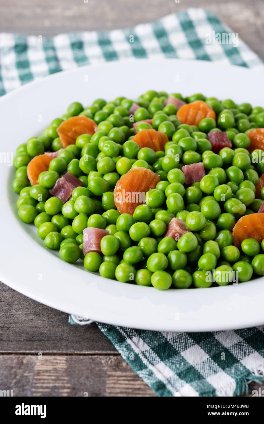 Green peas with serrano ham and carrot on wooden table Stock Photo - Alamy