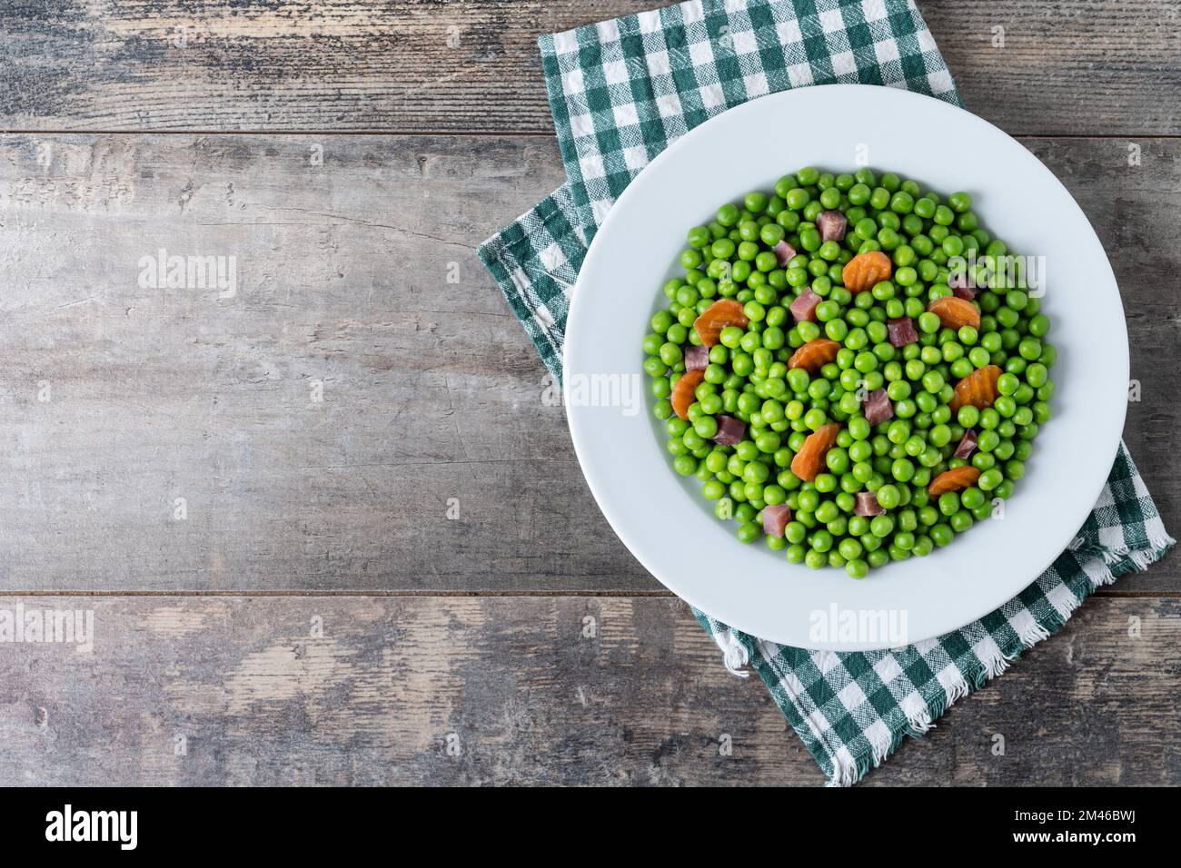 Green peas with serrano ham and carrot on wooden table Stock Photo - Alamy