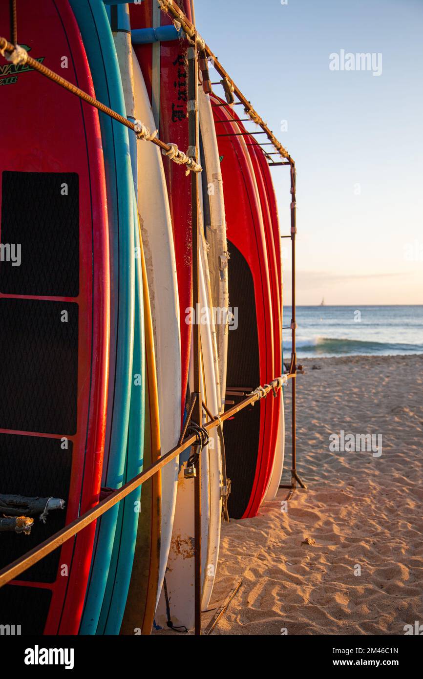 Surf boards stacked into racks on Waikiki Beach in the evening light ...