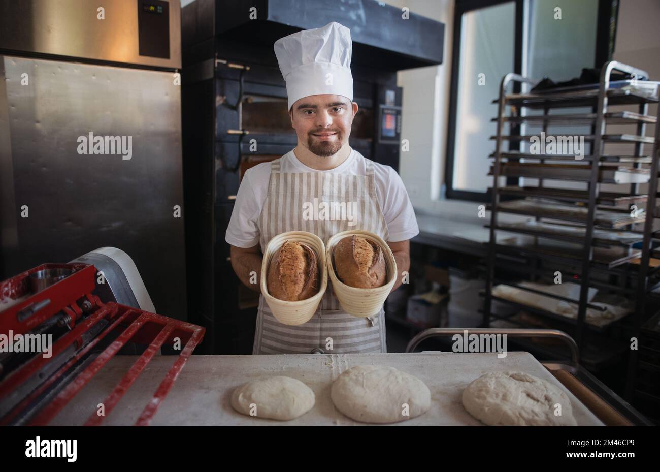 Young baker with down syndrome preparing pastries in bakery. Concept of ...