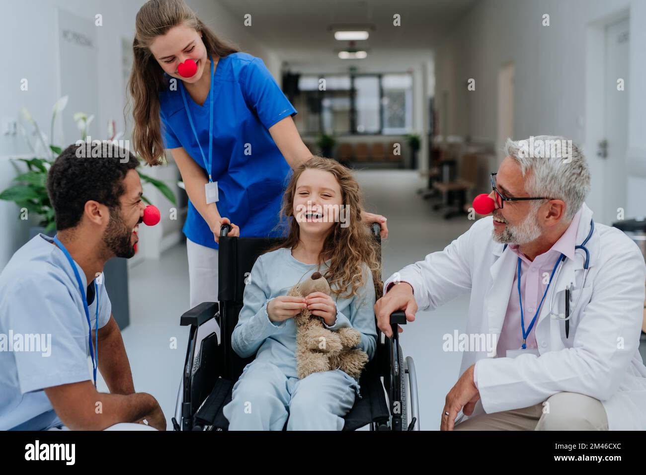 Happy doctors with clown red noses taking care about little girl Stock ...