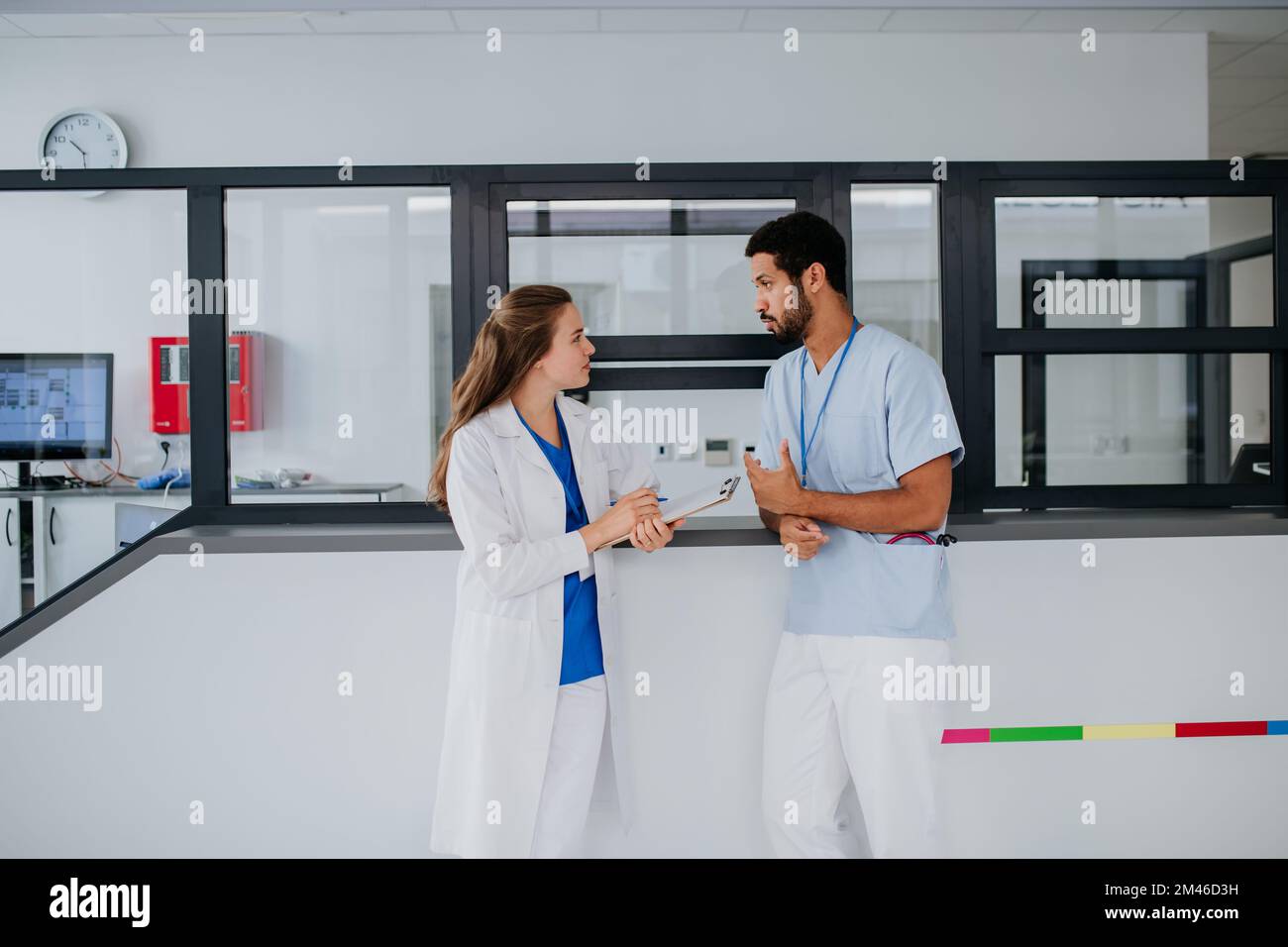 Young doctor talking at hospital reception with her colleague Stock ...