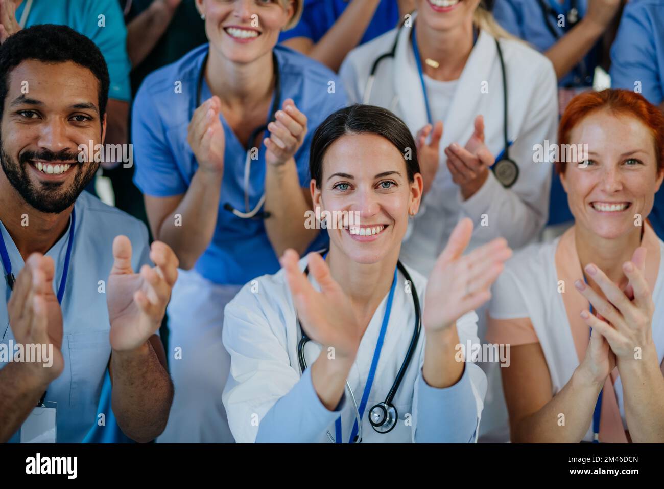 Portrait of happy doctors, nurses and other medical staff clapping in ...