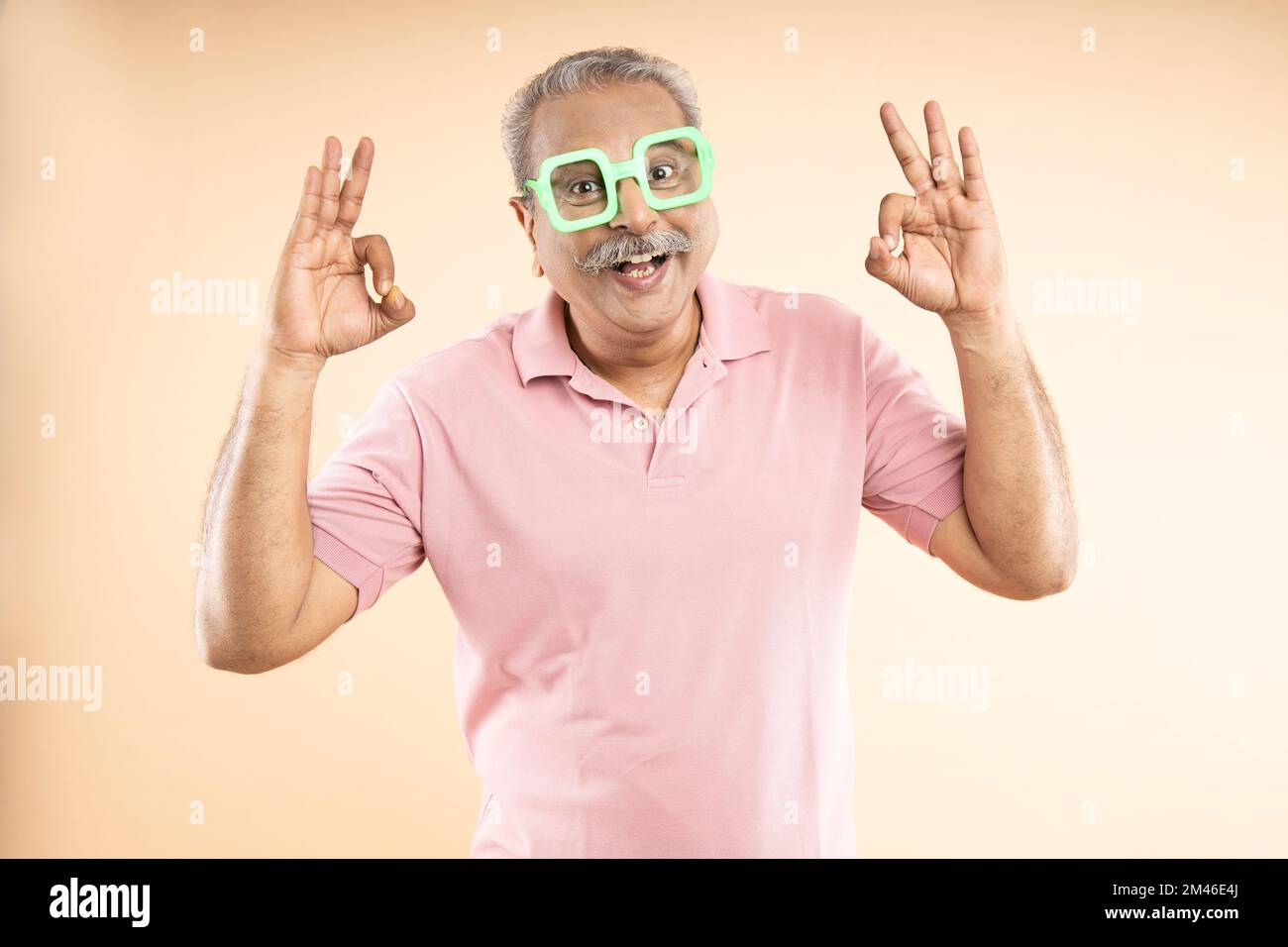 Happy senior indian man wearing funky sun glasses standing isolated on ...