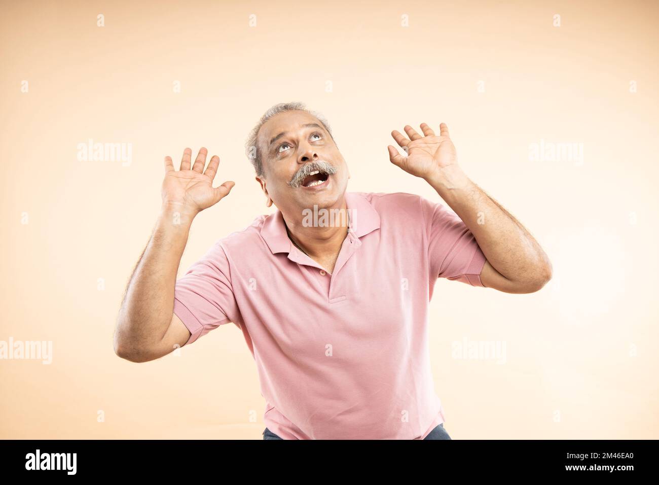 Senior indian man scared with his arms up like something falling from ...
